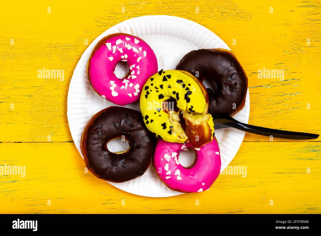 A full plate of donuts. Lots of colored donuts on a paper plate. View ...