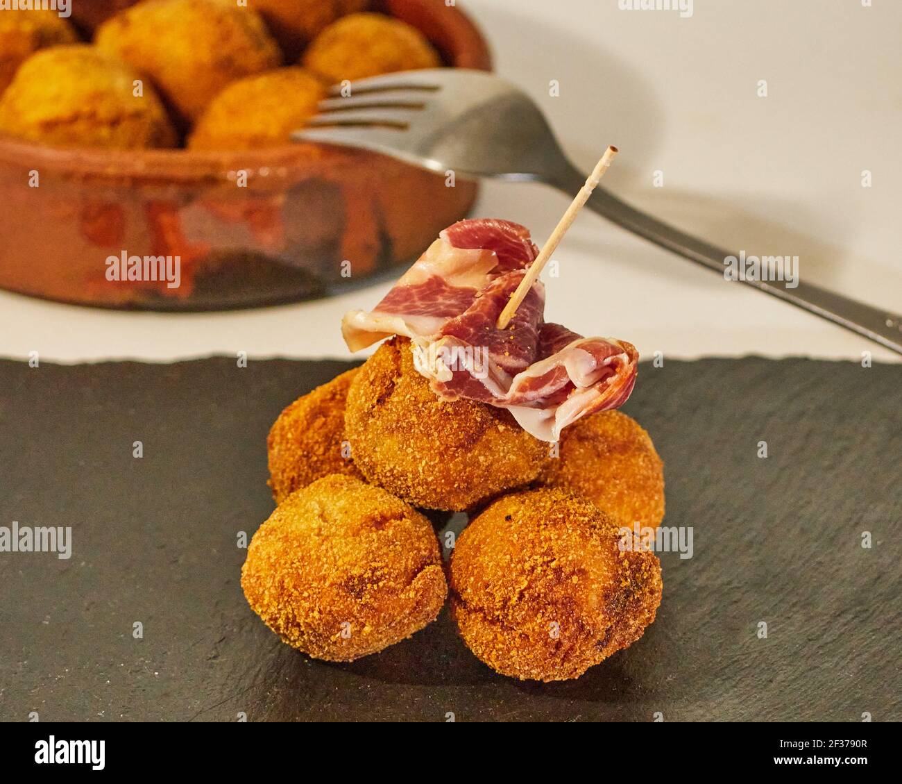 Pincho of several round croquettes with a slice of Iberian Ham on a ...