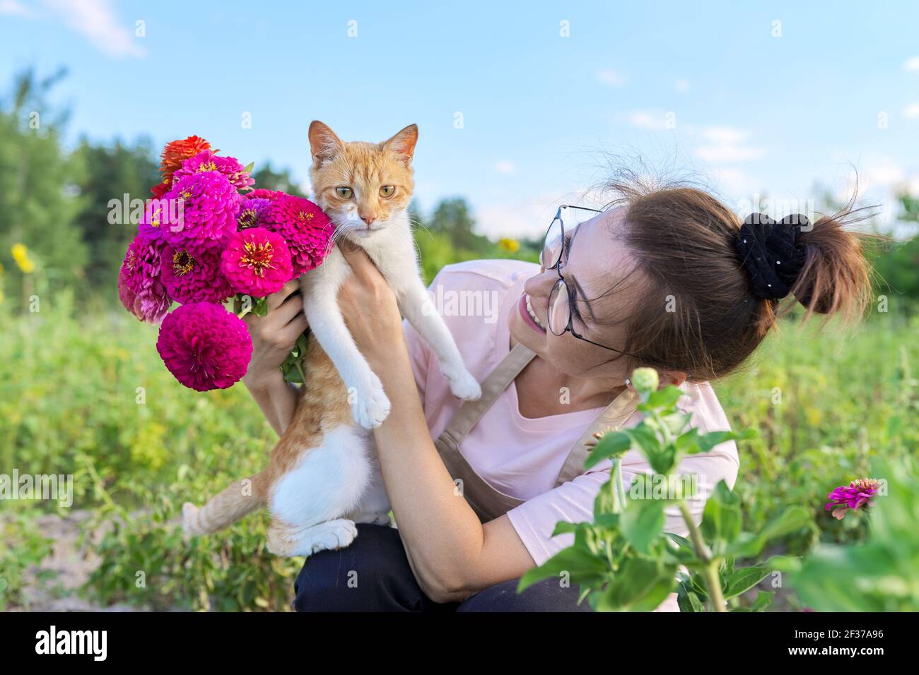 Happy middle-aged woman with pet red cat in her arms and bouquet of ...
