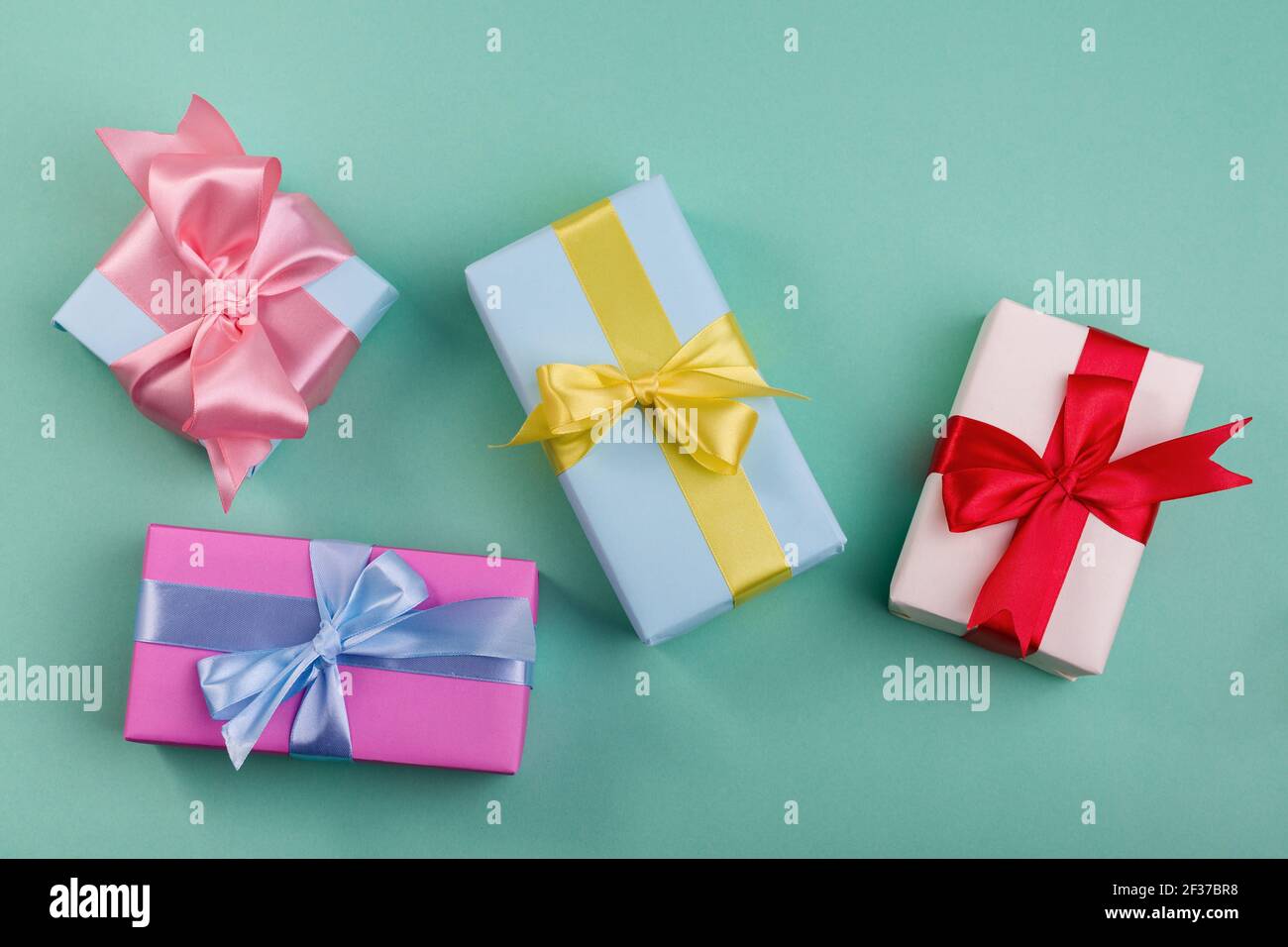 Different gift boxes with red, yellow. and blue bows on turquoise color ...