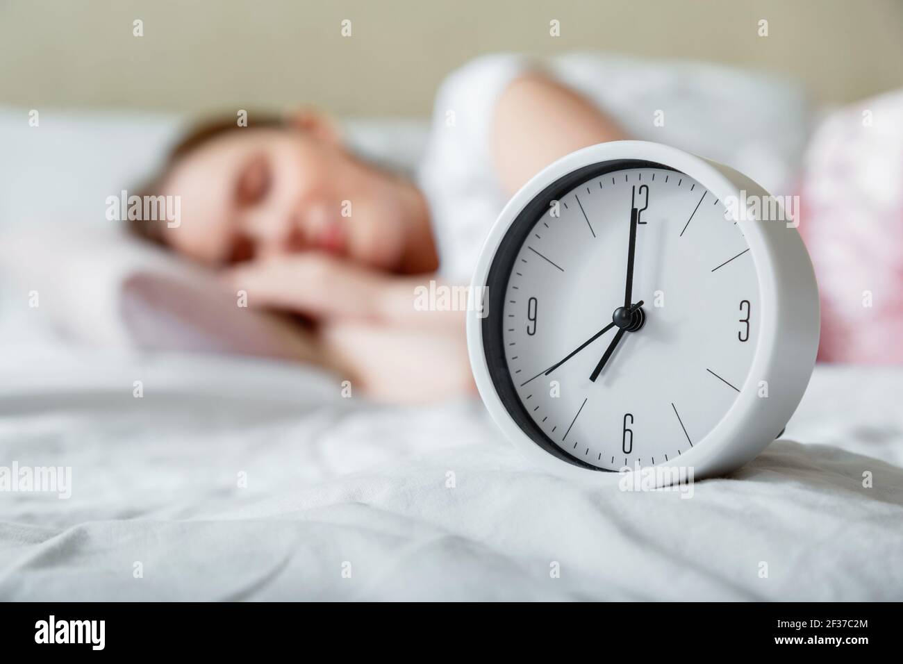 Happy young woman sleeping near bed side alarm clock. Calm healthy ...