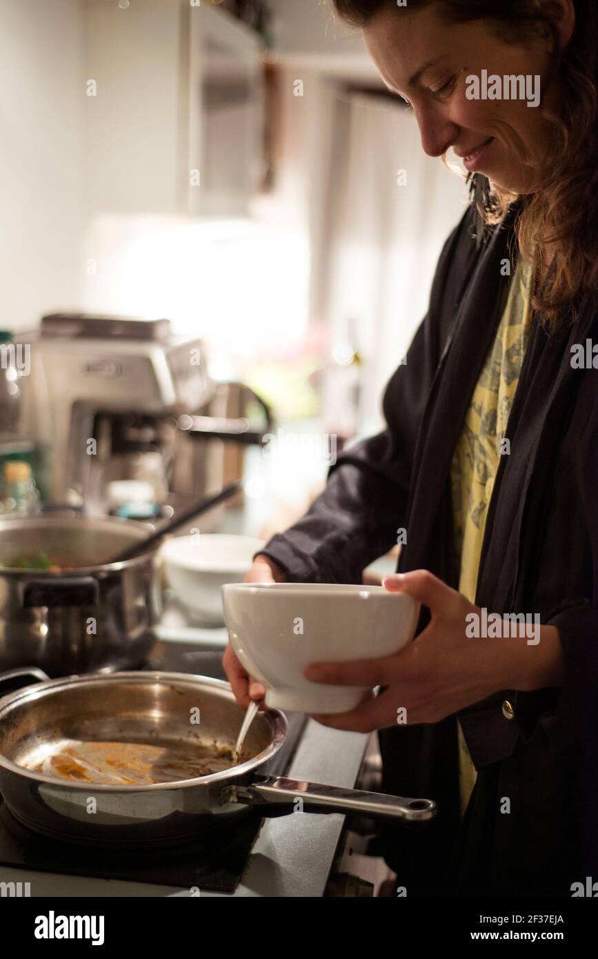 happy woman smiles as she serves healthy dinner at home in lockdown ...