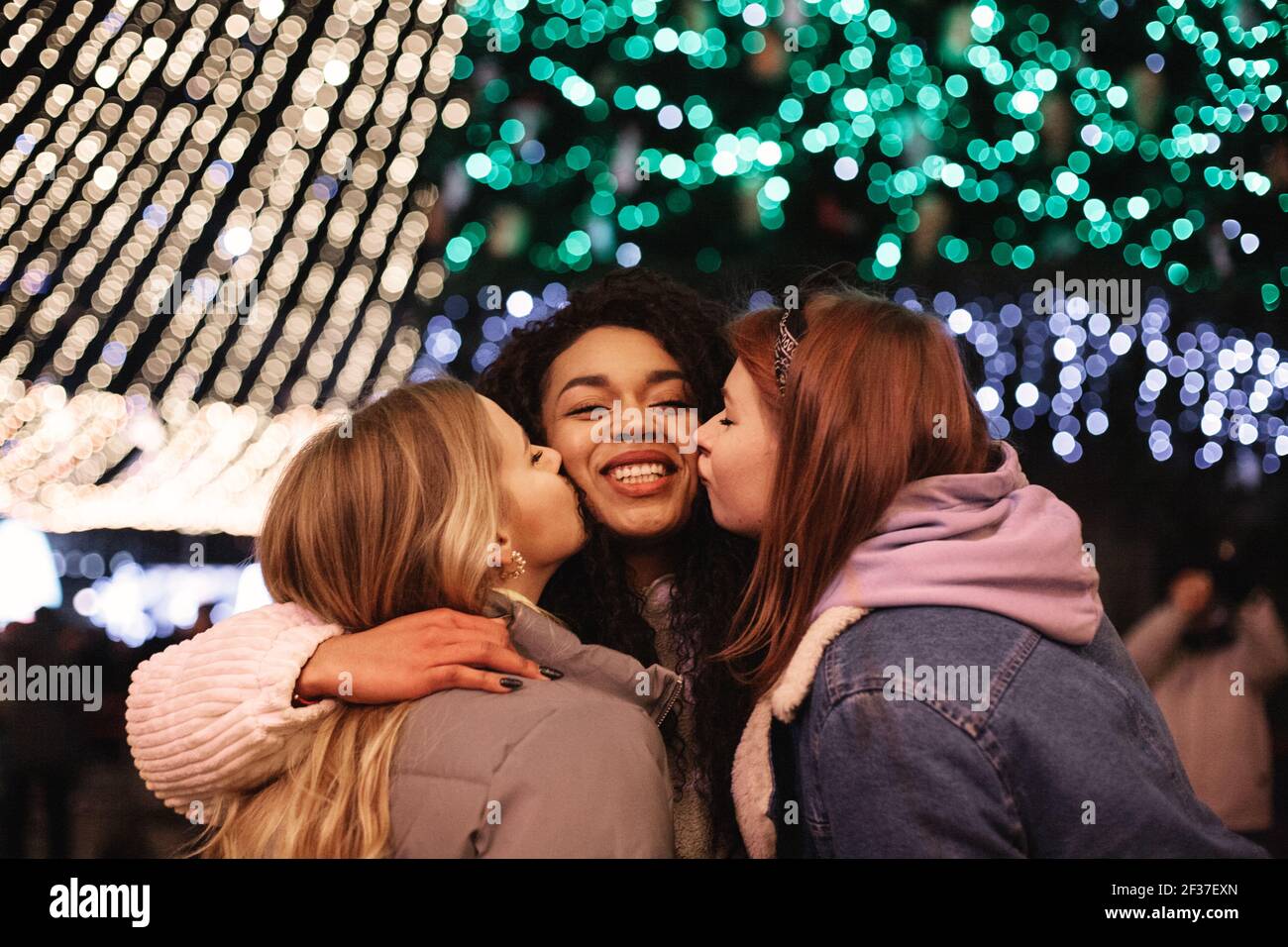 Woman kissing smiling friends cheek hi-res stock photography and images ...