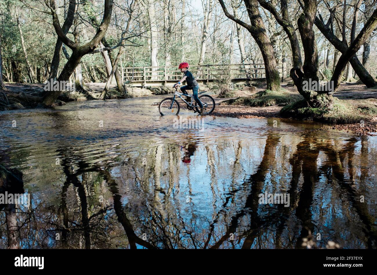 young boy cycling through a river to cross whilst mountain biking Stock ...