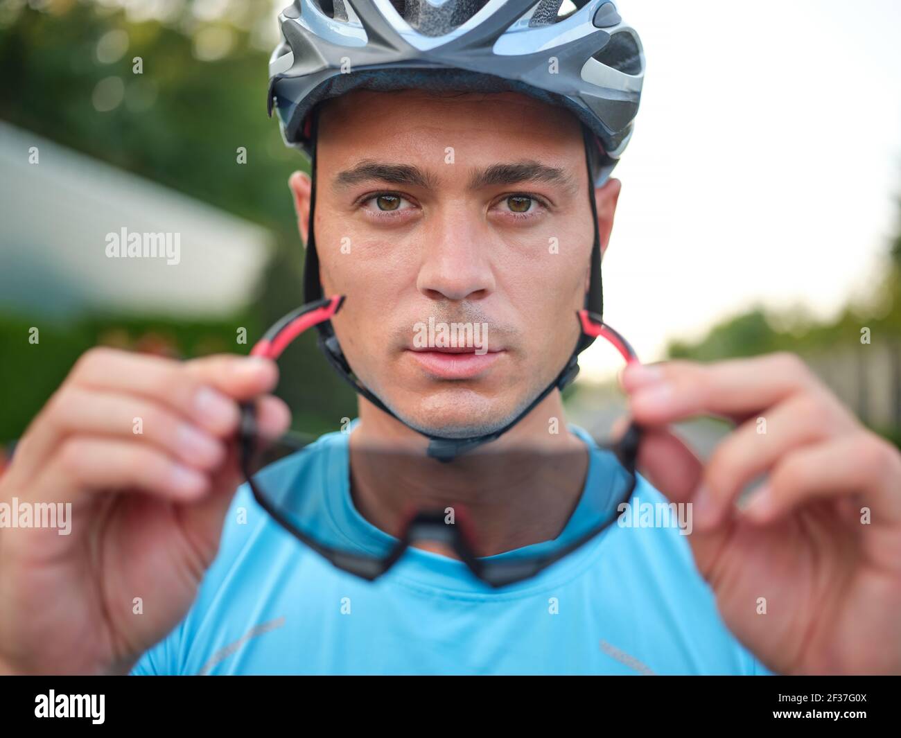 Portrait of handsome young male cyclist looking at camera while holding ...