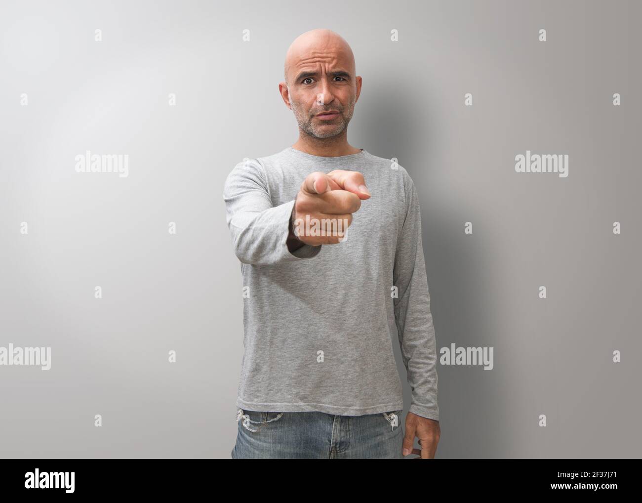 A Hispanic bald man pointing at the camera on a gray background Stock ...
