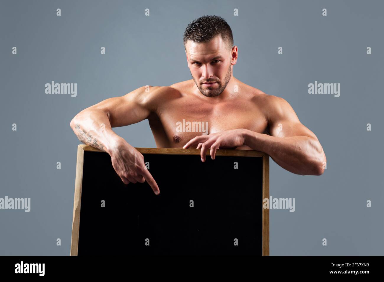 Fitness man with sign ad board. Strong bodybuilder macho holding blank ...