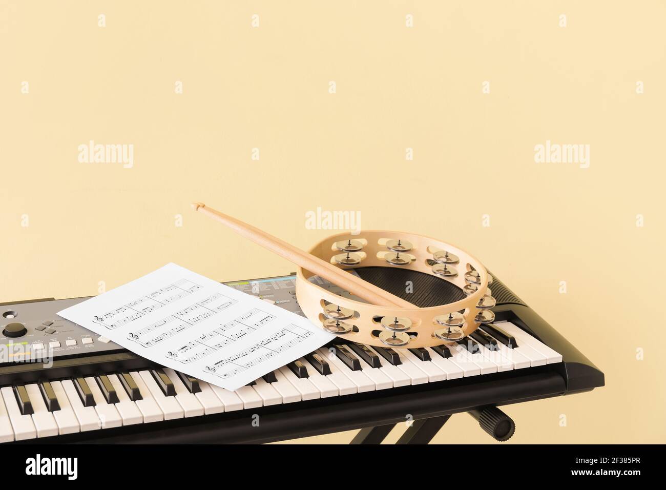 Synthesizer, tambourine, drumsticks and music notes on color background ...