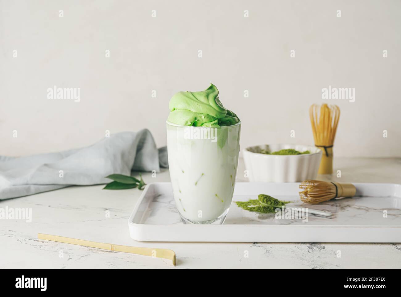 Composition with glass of tasty dalgona matcha latte on light ...