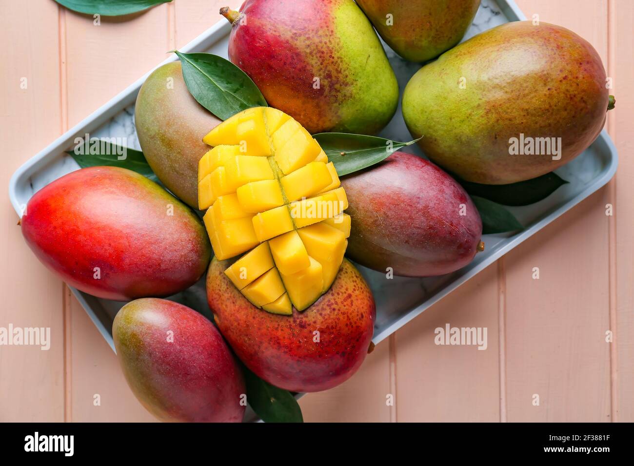 Tray with ripe mangoes on color wooden background, closeup Stock Photo ...