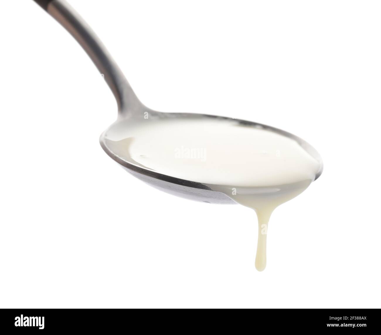 Spoon of sweet condensed milk on white background Stock Photo - Alamy