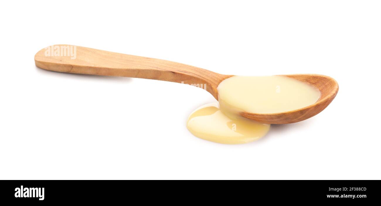 Wooden spoon of condensed milk on white background Stock Photo - Alamy