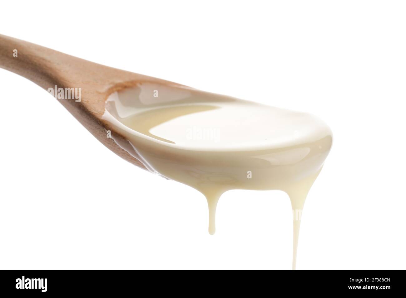 Wooden spoon of condensed milk on white background Stock Photo - Alamy