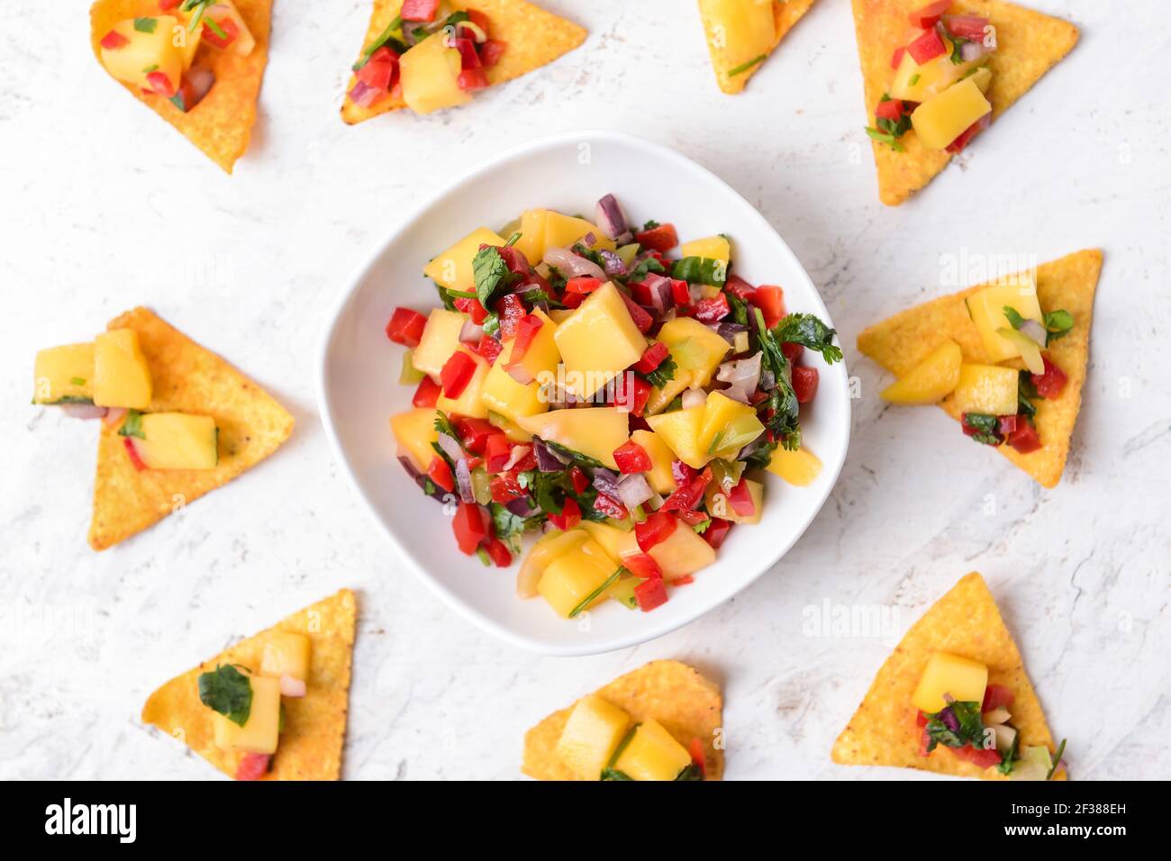 Frame made of nachos and bowl with fresh mango salsa on light ...