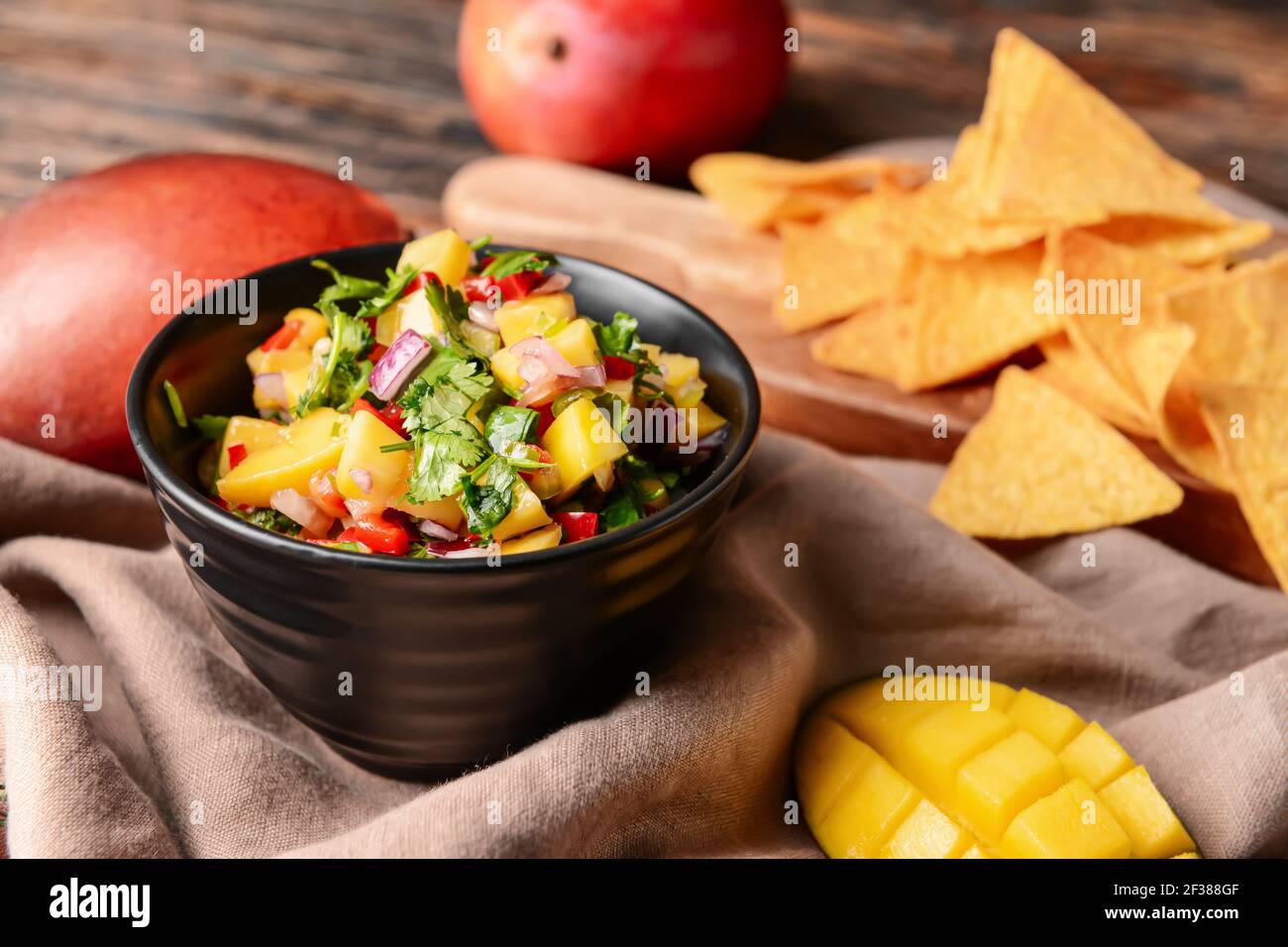 Bowl with fresh mango salsa and nachos on wooden background Stock Photo ...