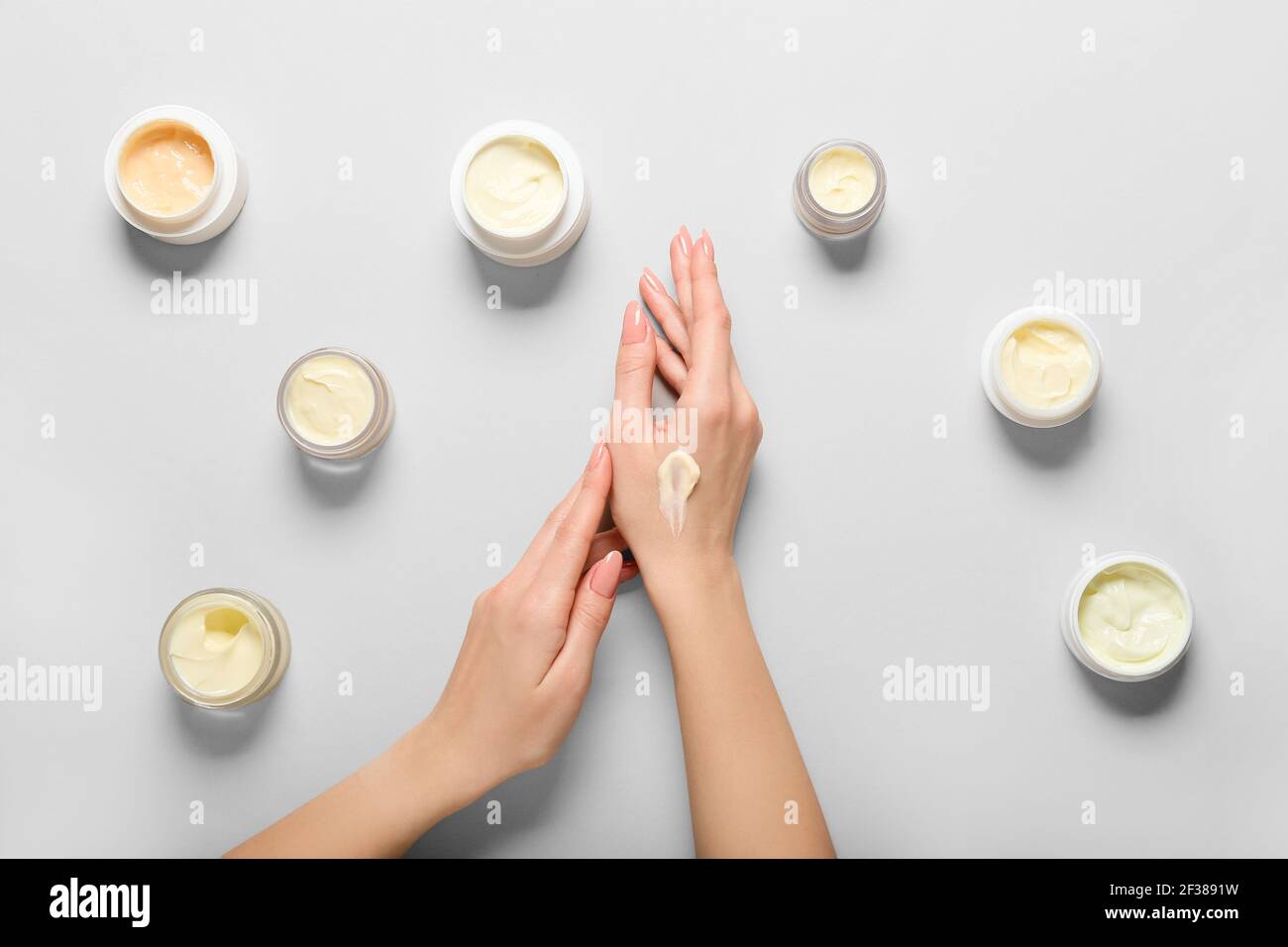 Female hands with jars of cream on light background Stock Photo - Alamy