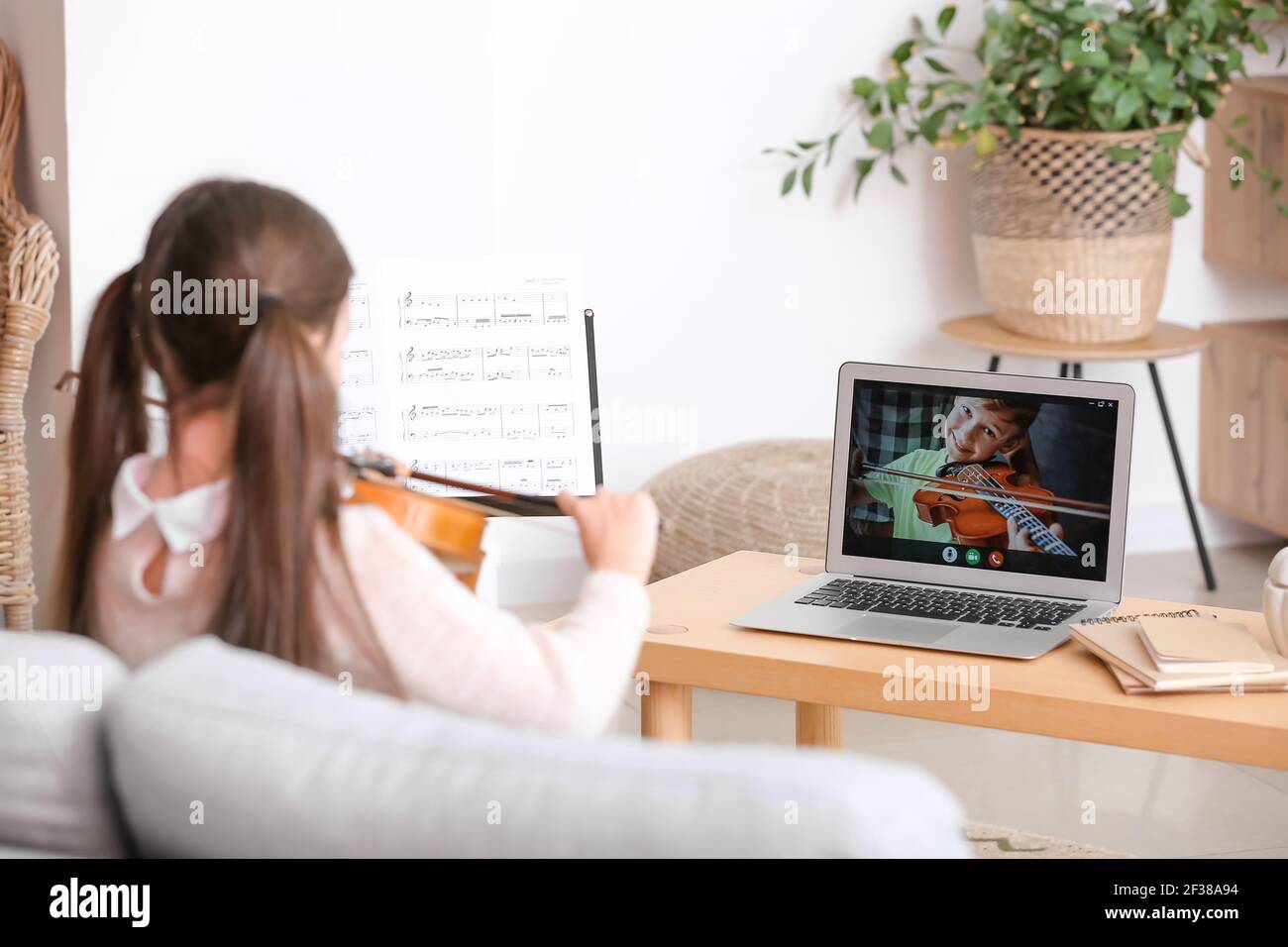 Little girl studying music with her friend online at home Stock Photo ...