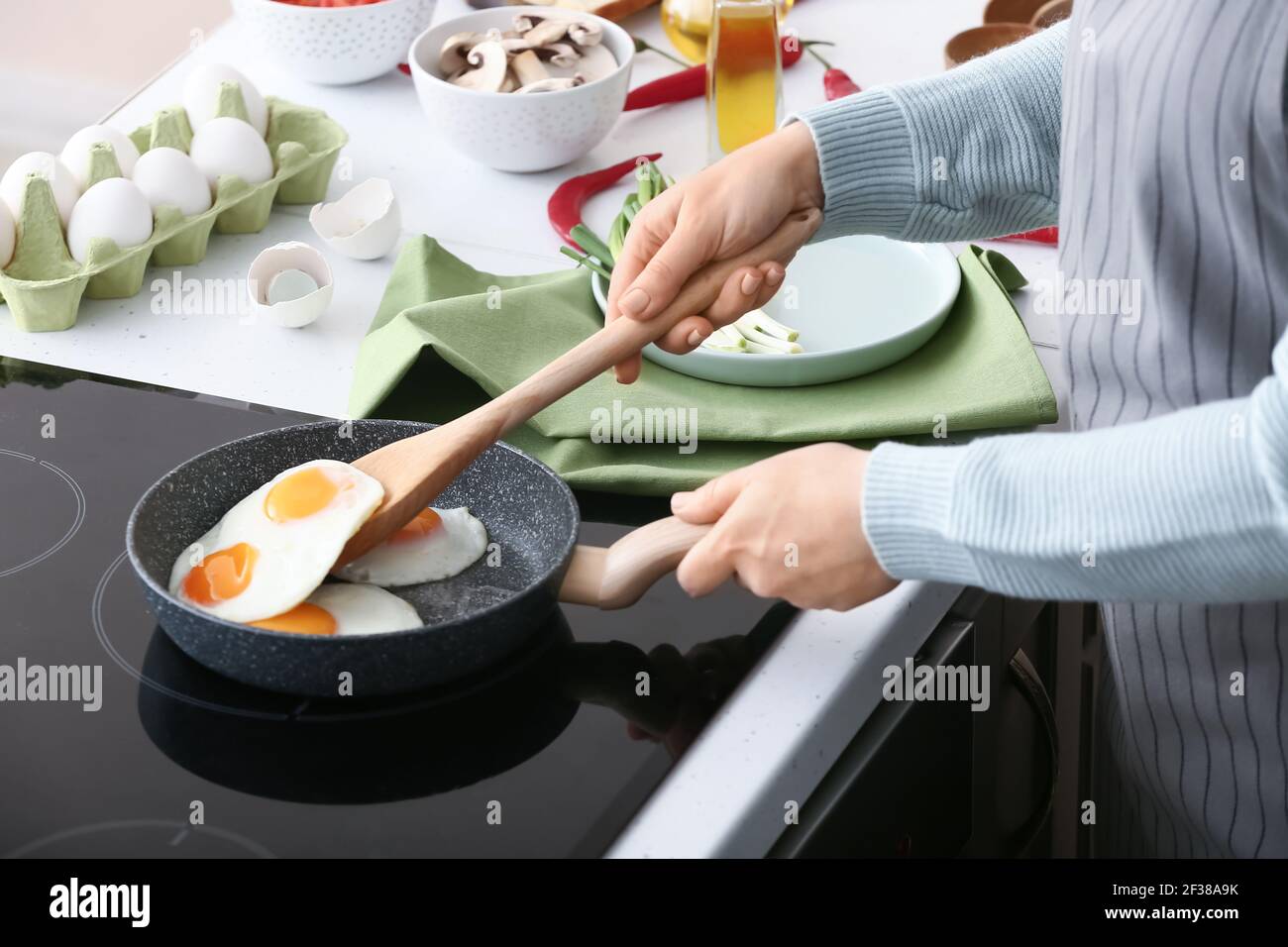 Woman cooking eggs in kitchen Stock Photo - Alamy