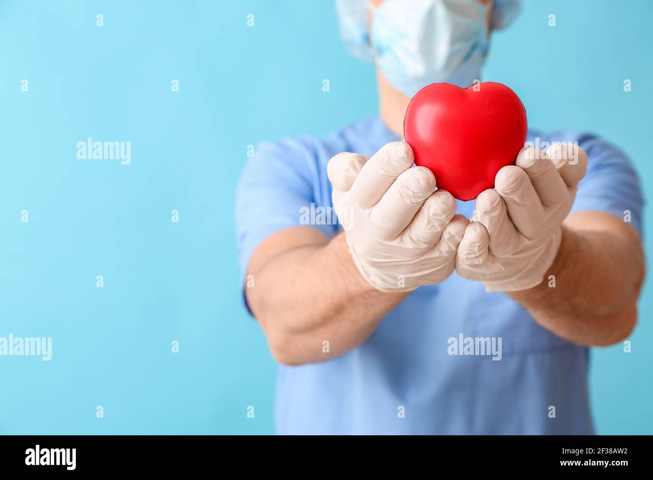 Cardiologist with red heart on color background Stock Photo - Alamy