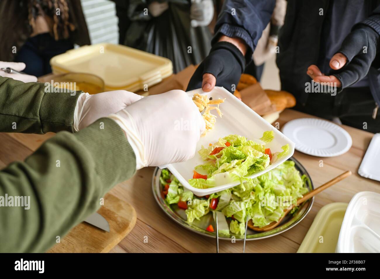 Volunteer giving food to homeless people in warming center Stock Photo ...