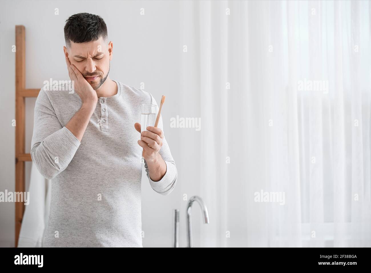 Man suffering from pain while brushing teeth in morning Stock Photo - Alamy
