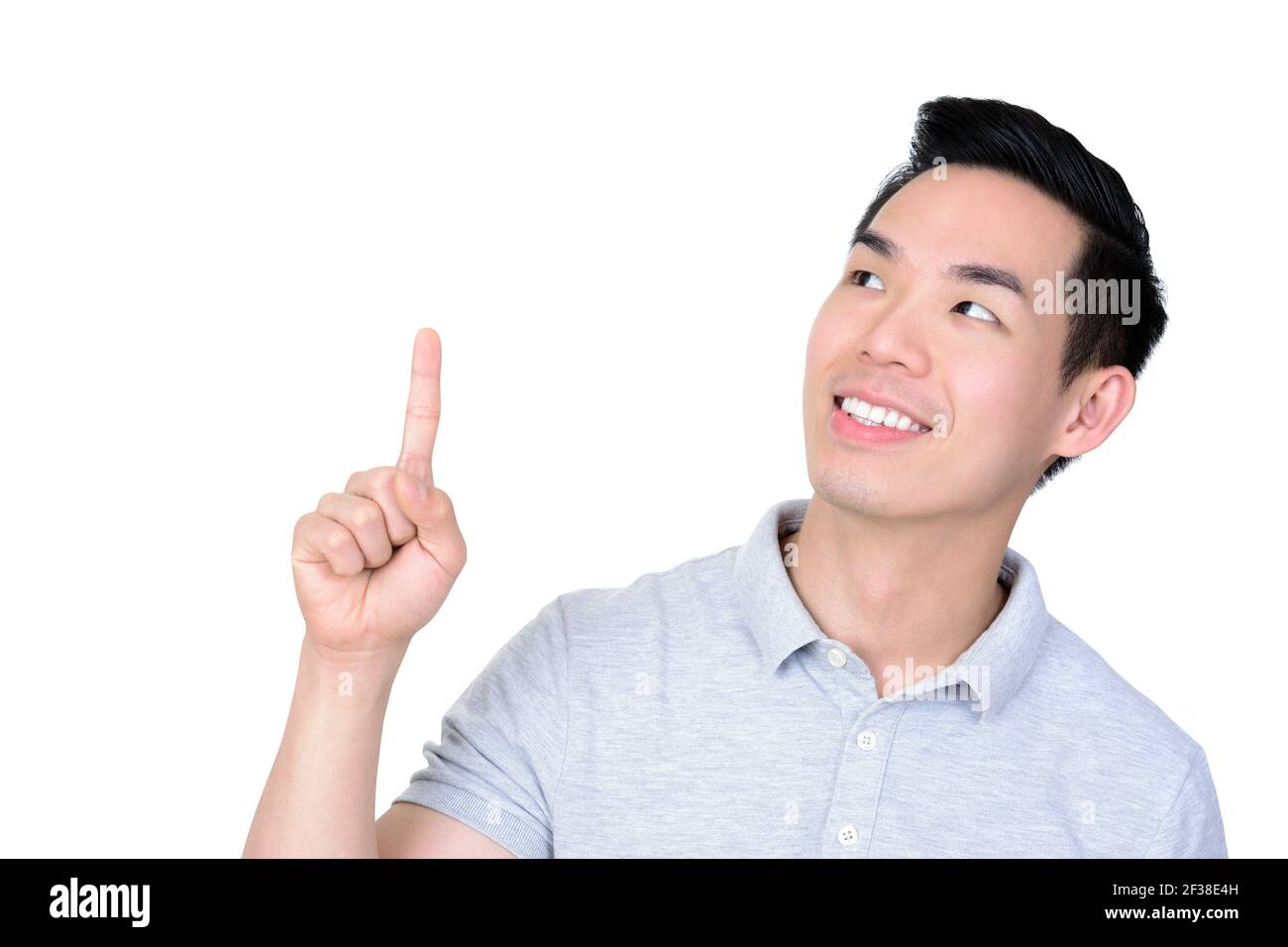 Smiling young Asian man looking and pointing up at empty space ...