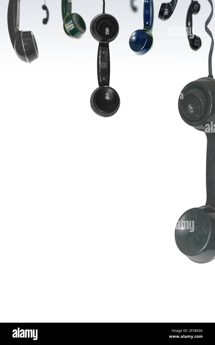 classic telephone receivers hang from the ceiling on a white background ...