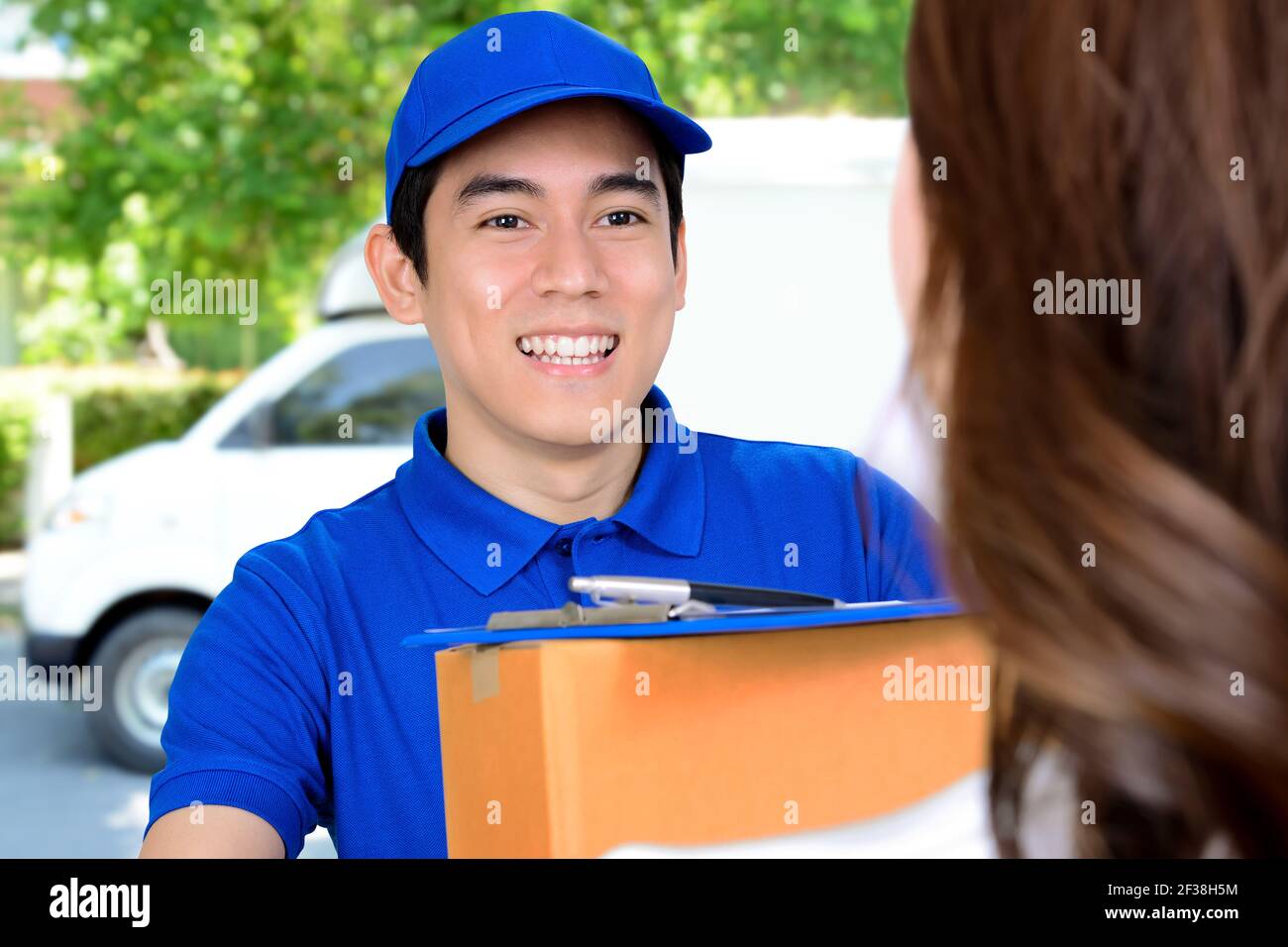 Smiling delivery man delivering a package Stock Photo - Alamy