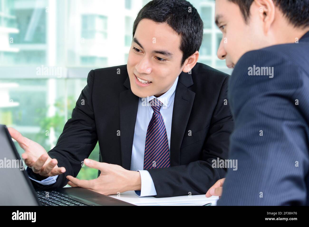 Businessmen discussing work while looking at laptop computer Stock ...