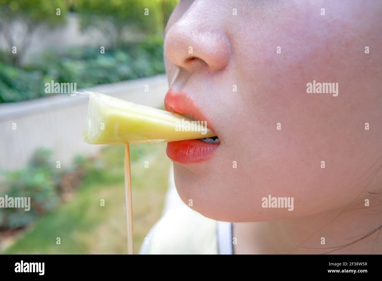 Close-up of a girl eating sour mango Stock Photo - Alamy