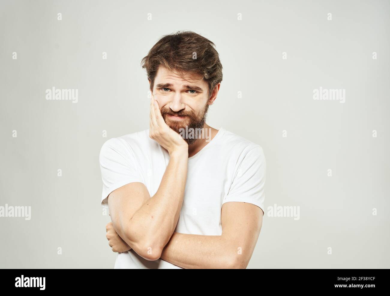 Man touches face with hands emotions model light background Stock Photo ...