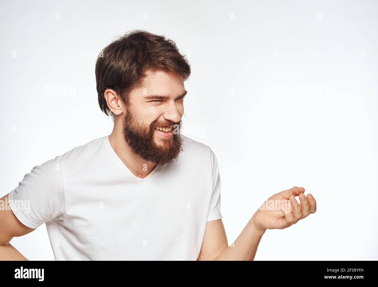 Happy man gestures with his hands on a white background in a light T ...