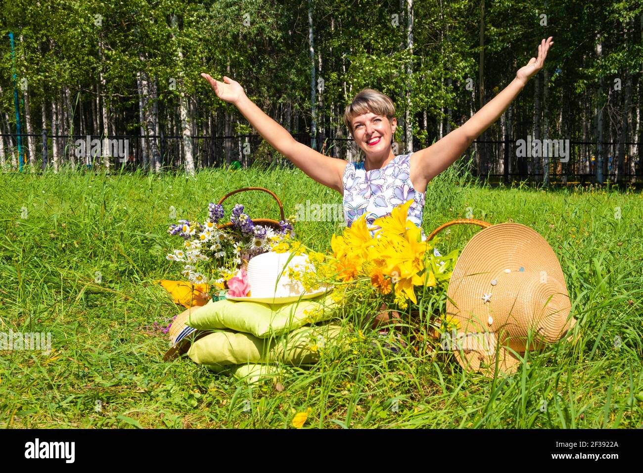 Gorgeous young girl in a sundress lying on grass and having a picnic in ...