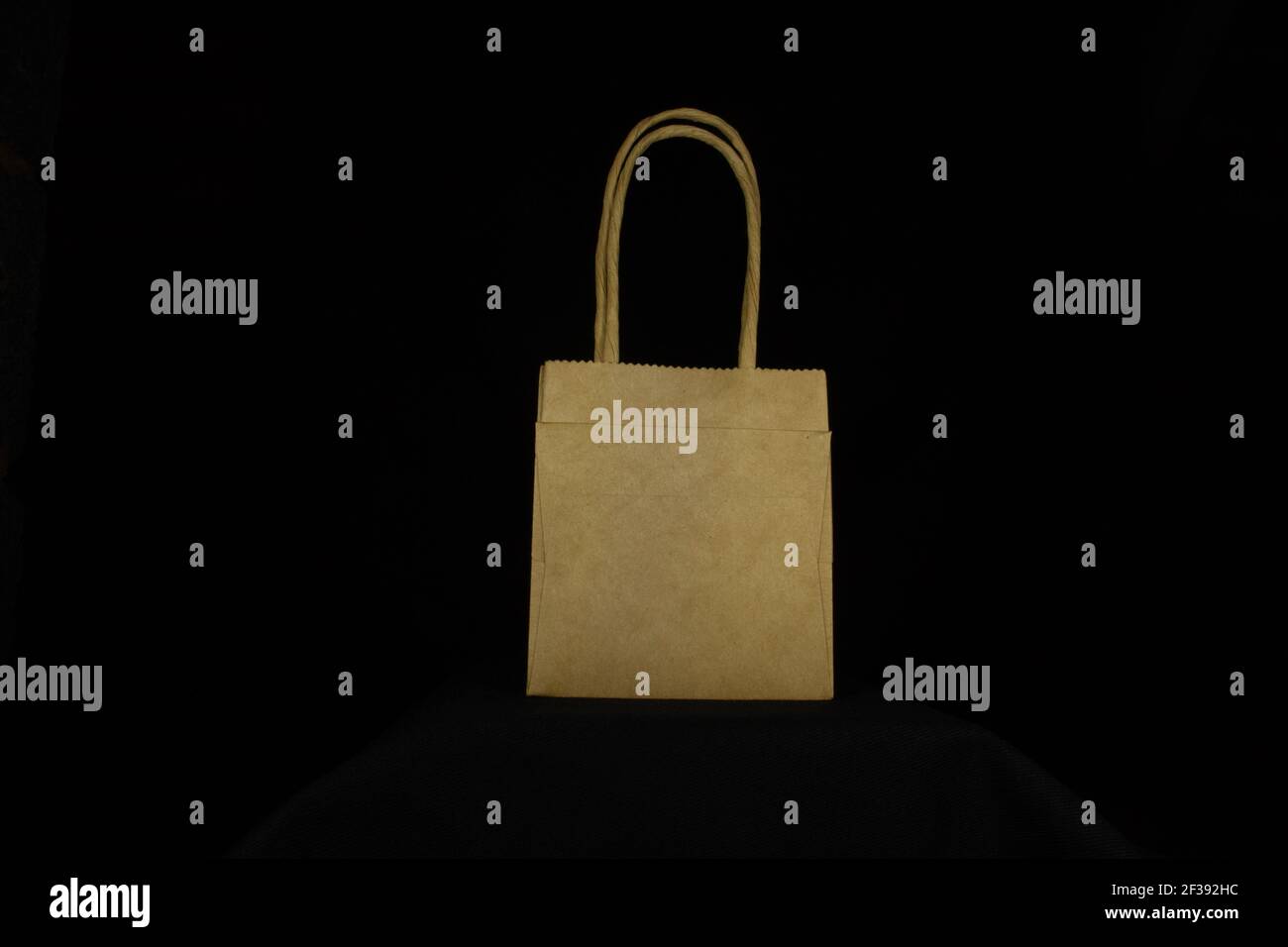 single closed mini recycled brown paper bag with paper handles isolated ...