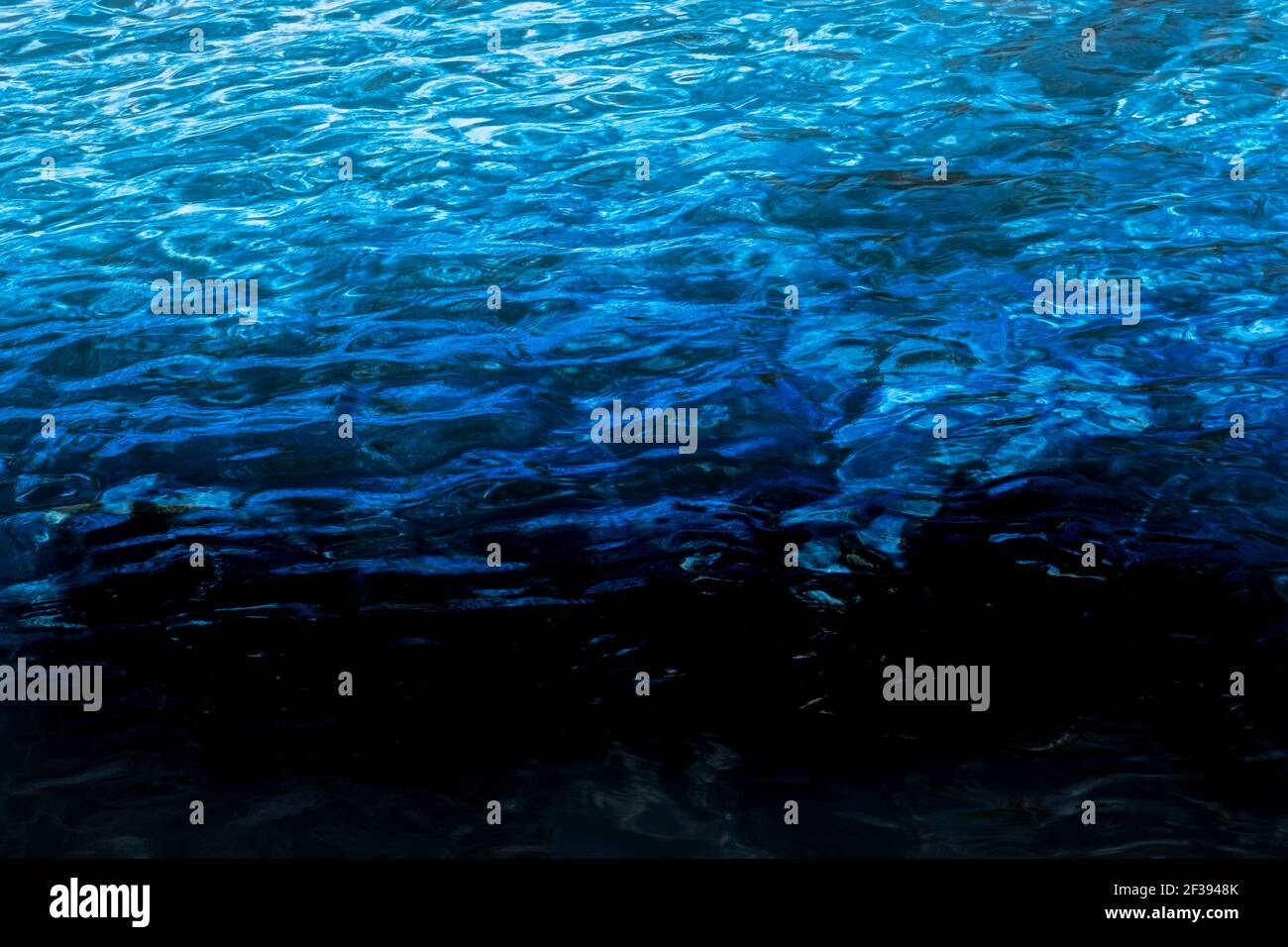 Water in a pool with slightly moving waves and reflections of the sun ...