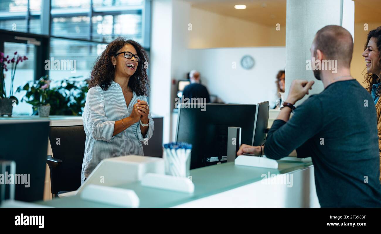 Smiling receptionist assisting people standing at municipal office ...