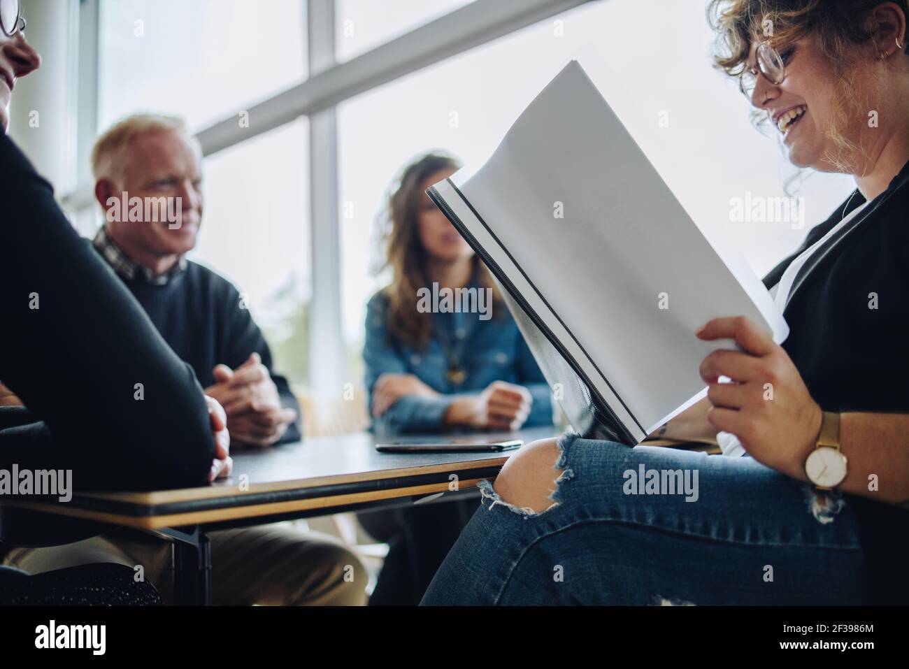Smiling business woman reading a paper with her colleagues sitting by ...