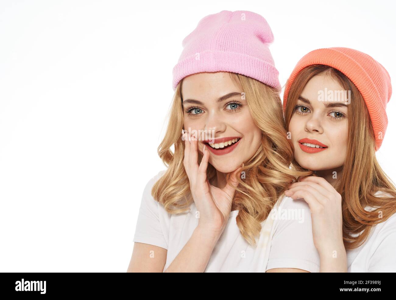 Two sisters in multi-colored caps hug together Friendship communication ...