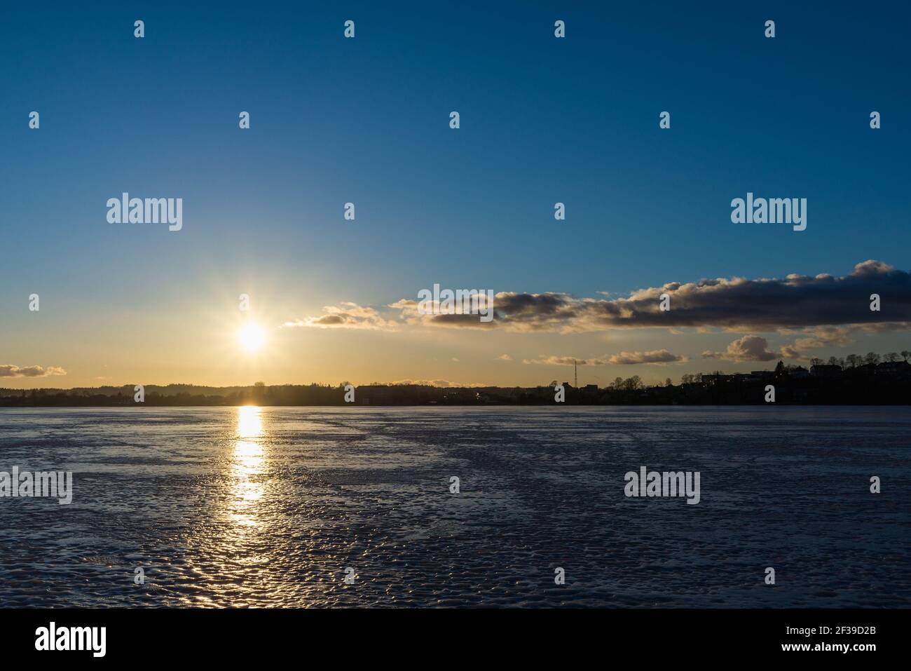 Winter landscape with frozen lake at sunrise or sunset. Lake glistening ...