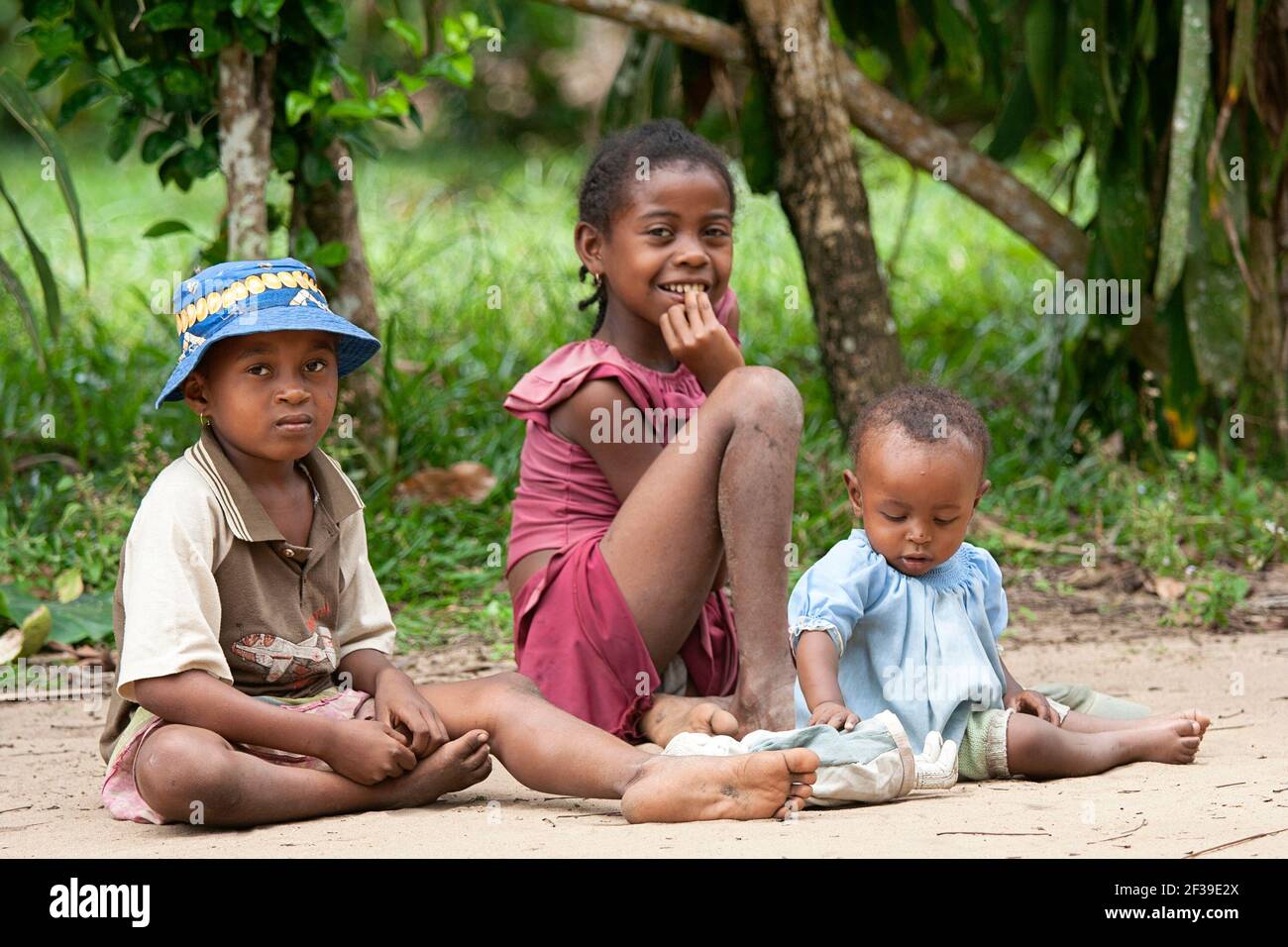 Portrait of three Malagasy children sitting on the ground, Maroansetra ...