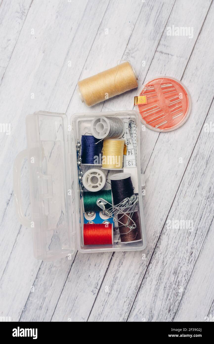 skein of multicolored thread in a plastic box wooden background needles ...
