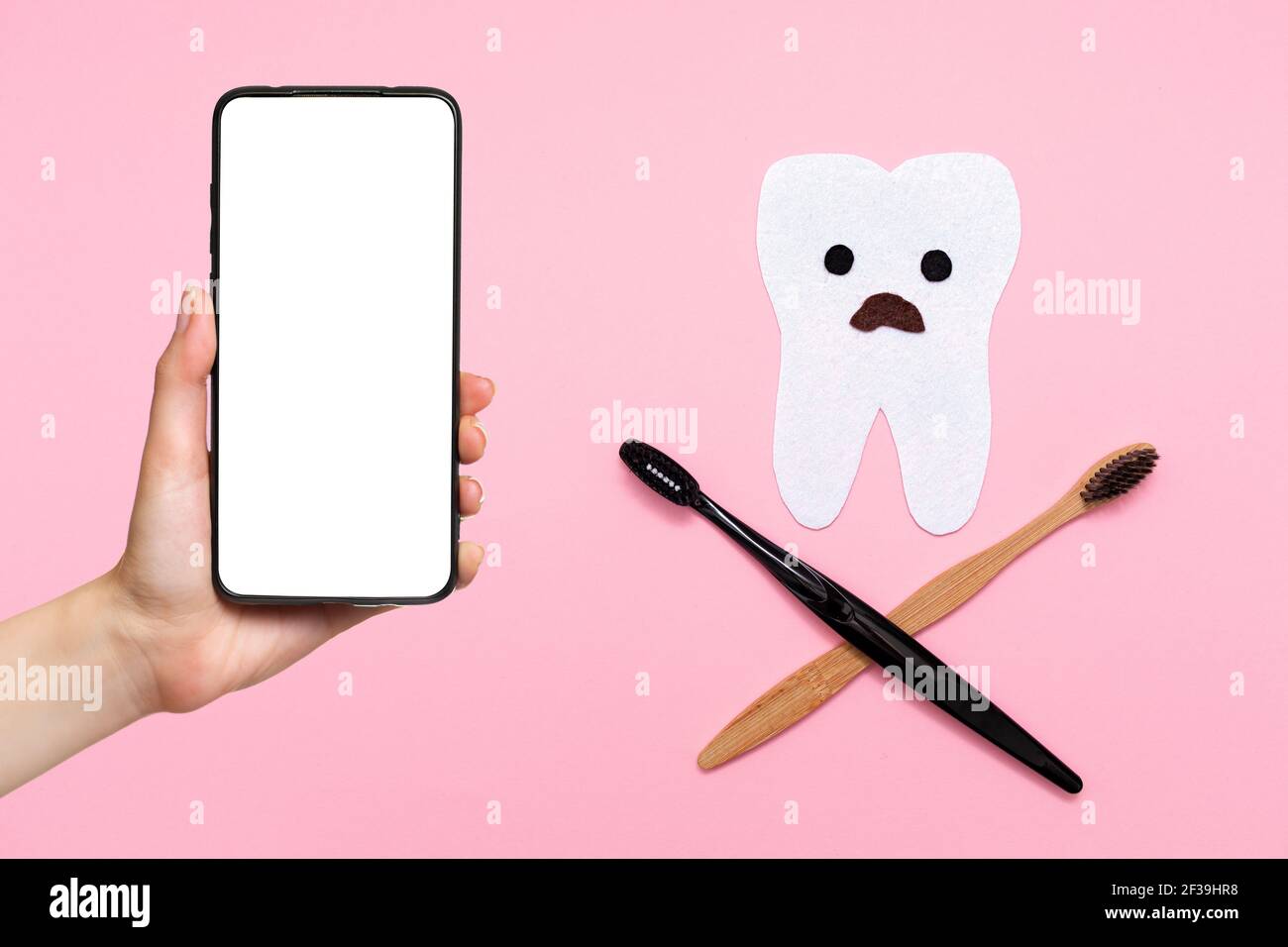 A startled tooth, cut out of felt with crossed toothbrushes, in the ...