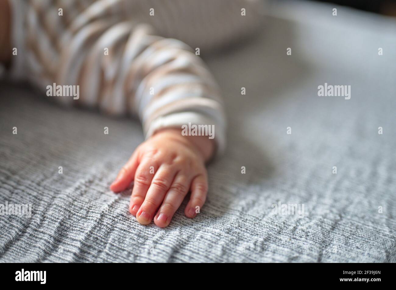 Cute little baby hand while lying on bed Stock Photo - Alamy