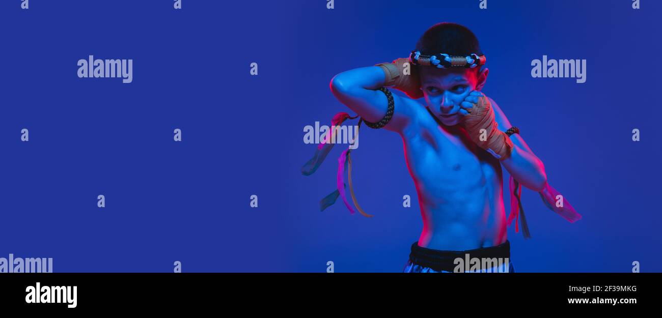 Young boy thai boxer posing over blue background in neon light Stock ...