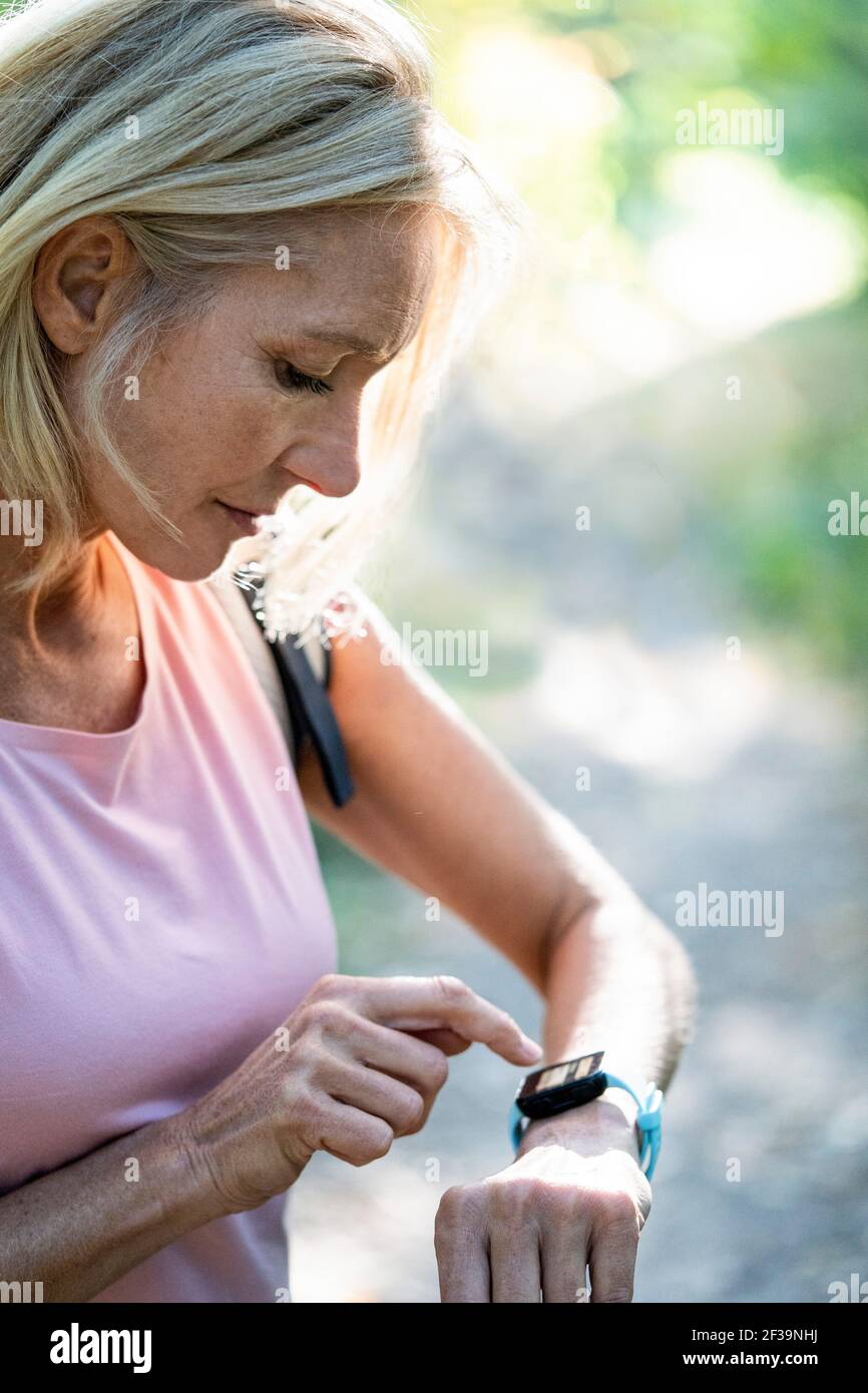 Mature woman operating smart watch in forest Stock Photo - Alamy