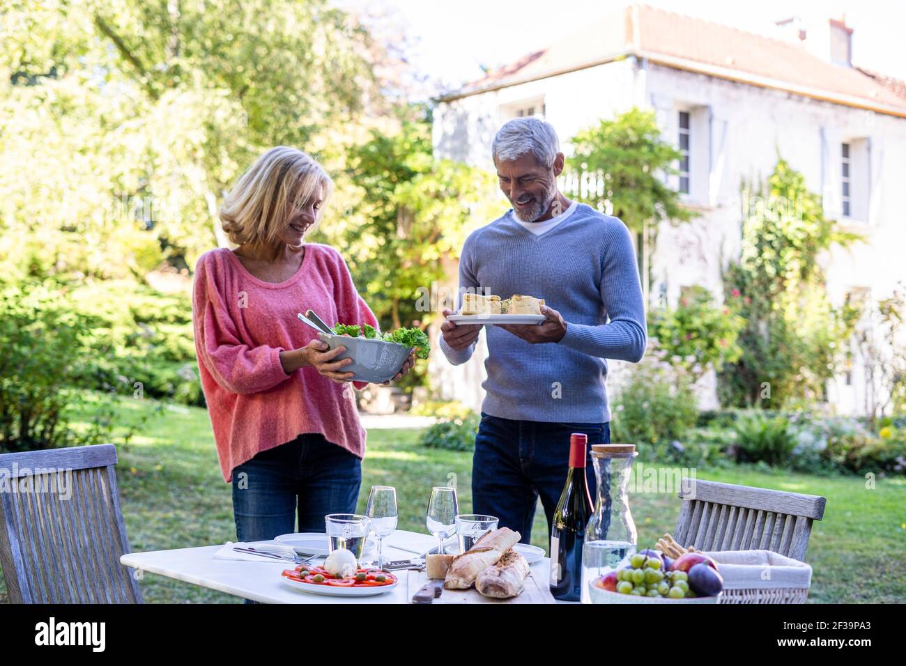 Smiling mature couple bringing food at table Stock Photo - Alamy