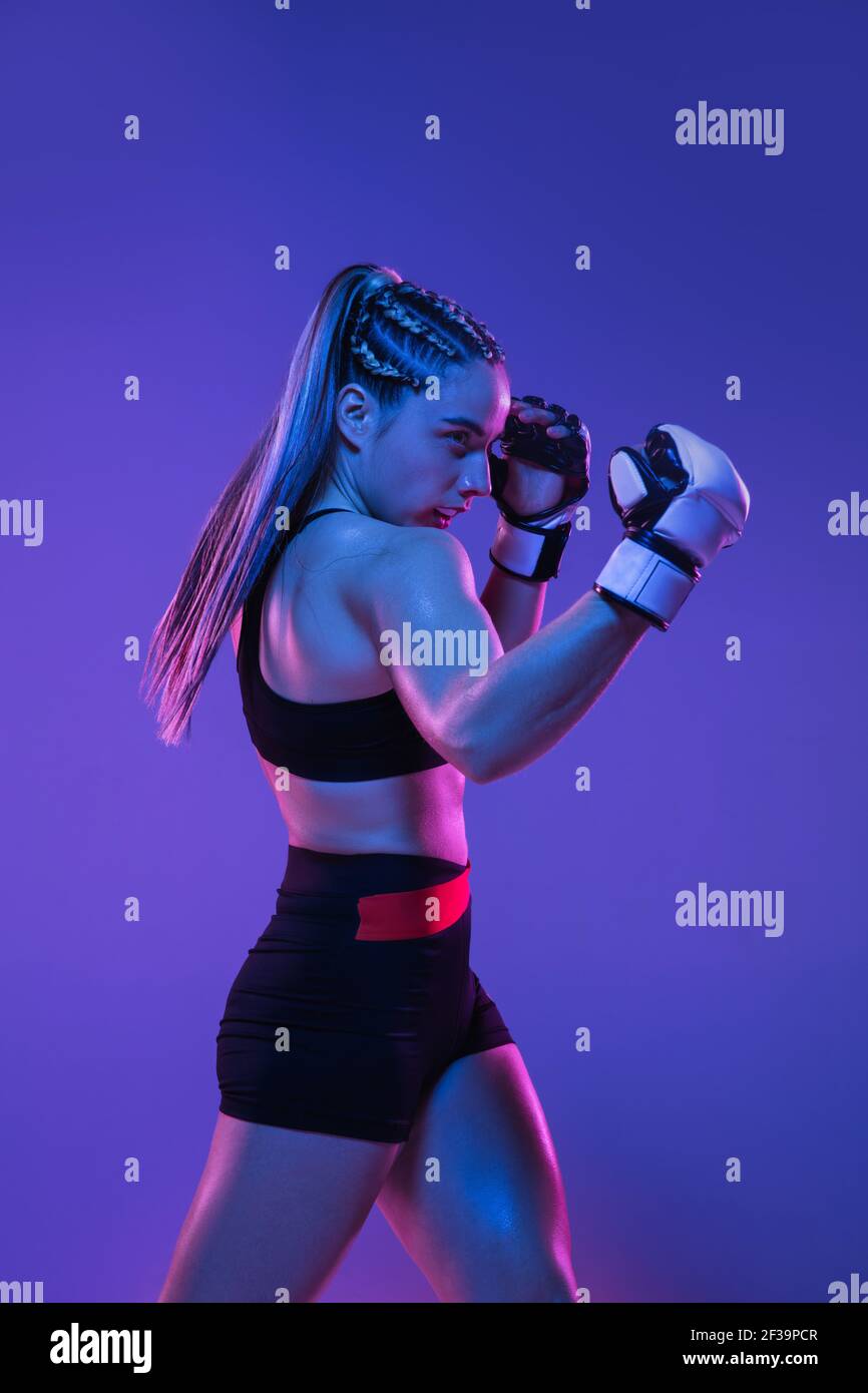 Young female MMA fighter posing isolated over blue-pink background in ...