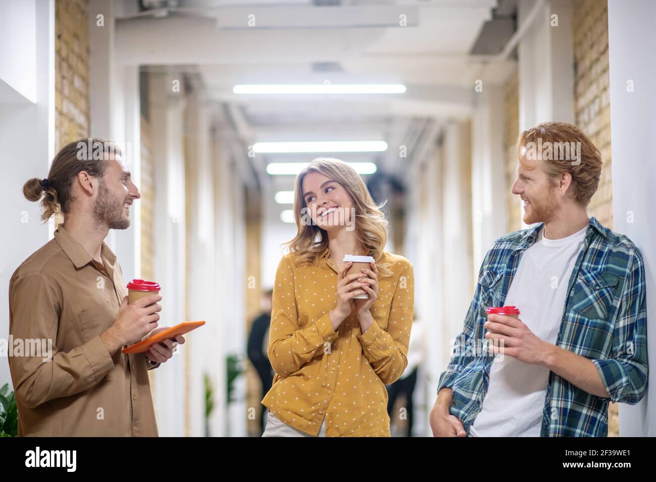 Coffee break. Young coworkers talking and smiling during the coffee ...