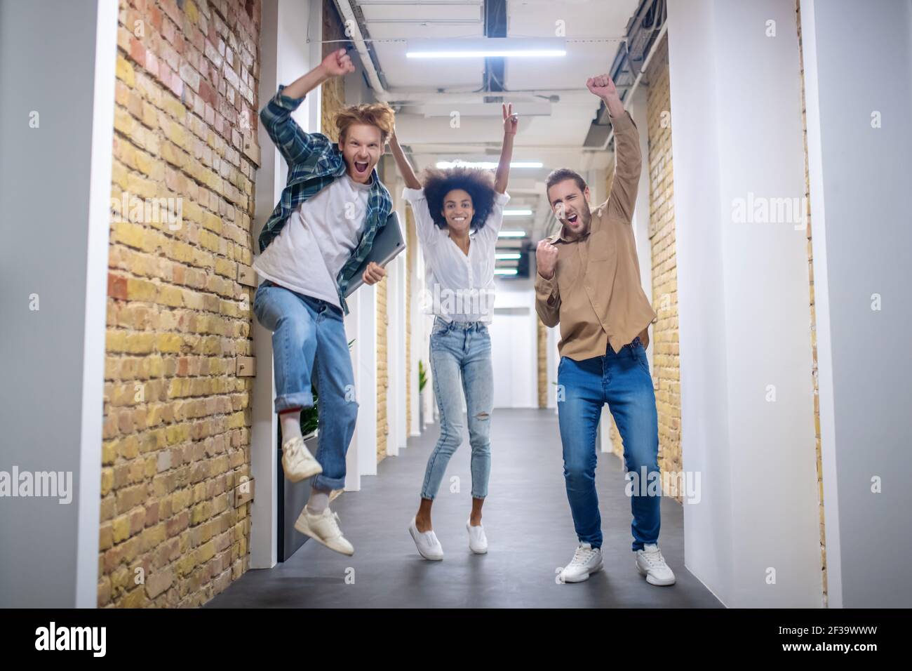 Happy people. Young people looking happy and jumping in the corridor ...