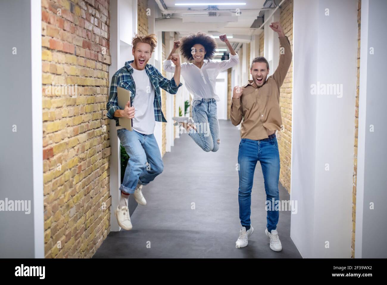 Happy people. Young people looking happy and jumping in the corridor ...